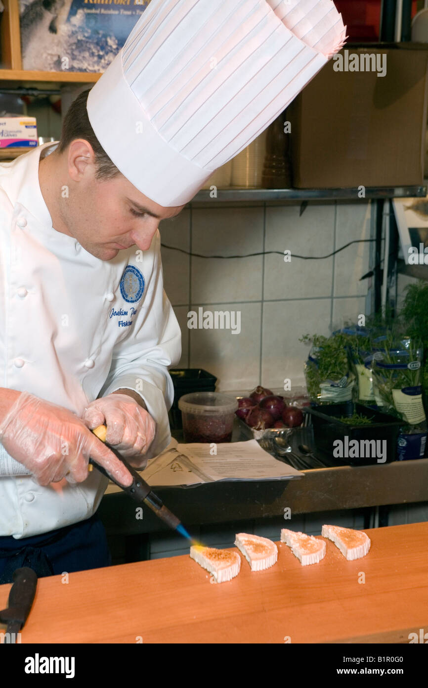 Chef puts a final touch with a small blowtorch browning the cake Stock ...