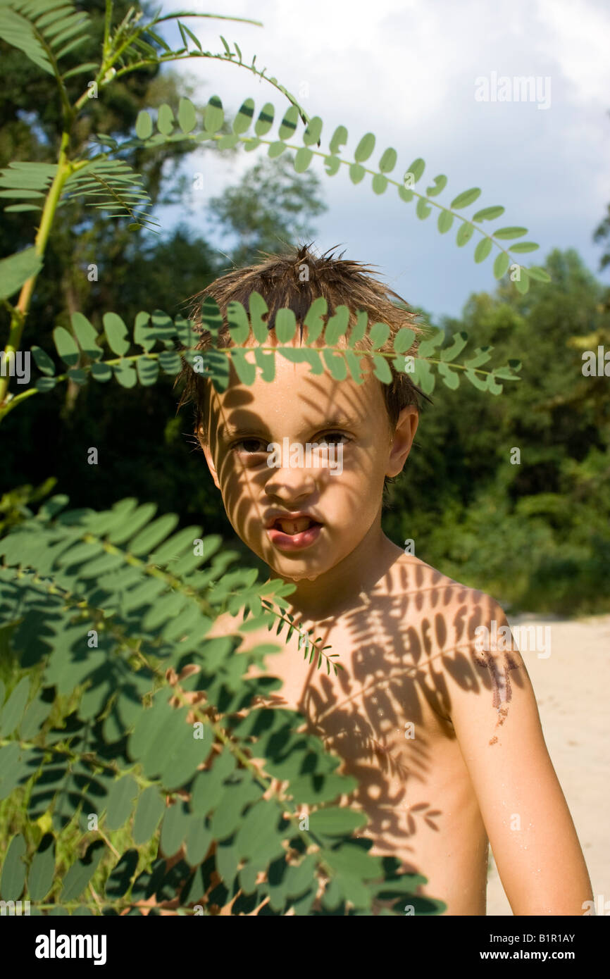 Boy standing in shadow with leaf pattern Stock Photo - Alamy