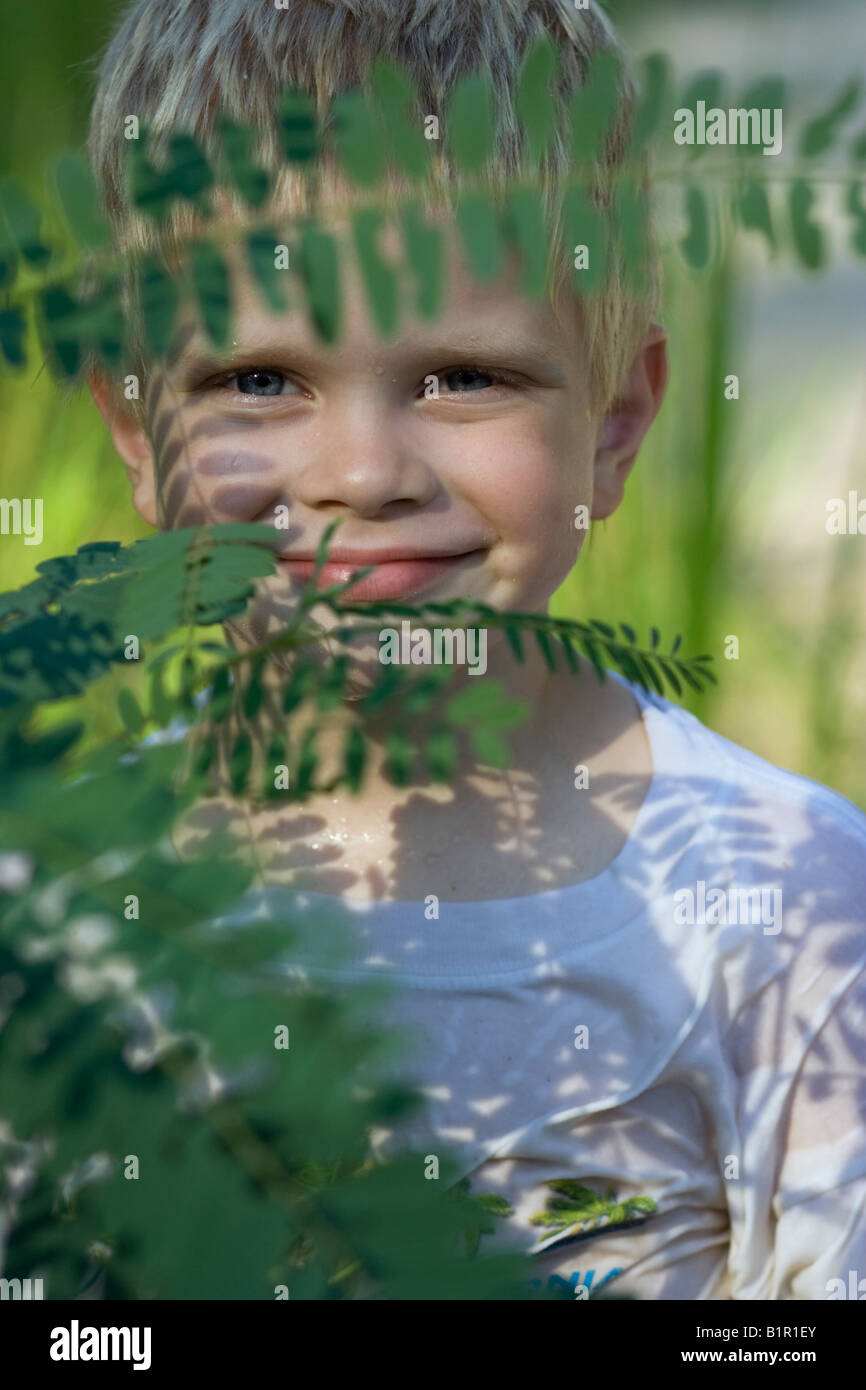 Boy standing in shadow with leaf pattern Stock Photo - Alamy