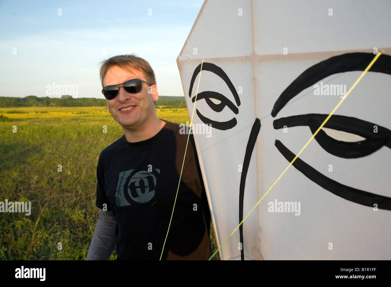 An adult man is playing with his self-made kite in a field Stock Photo ...