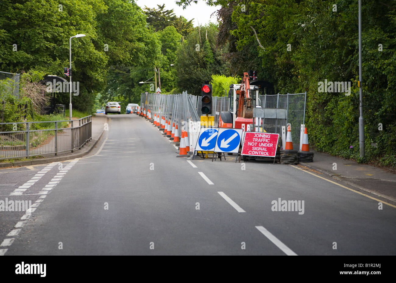 Road works and temporary red traffic lights, barriers and road cones ...