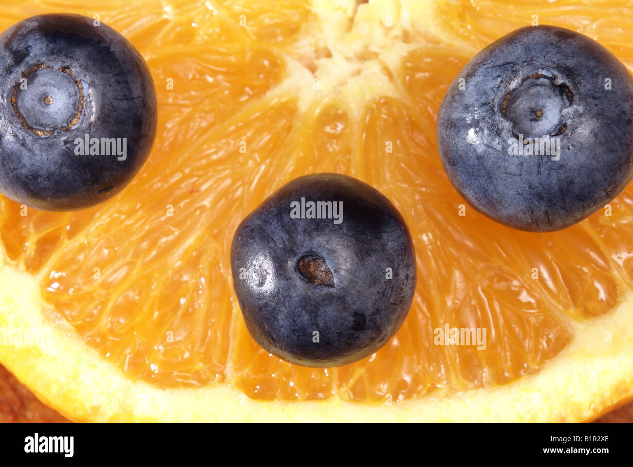 Three blueberries on Orange slice Stock Photo - Alamy