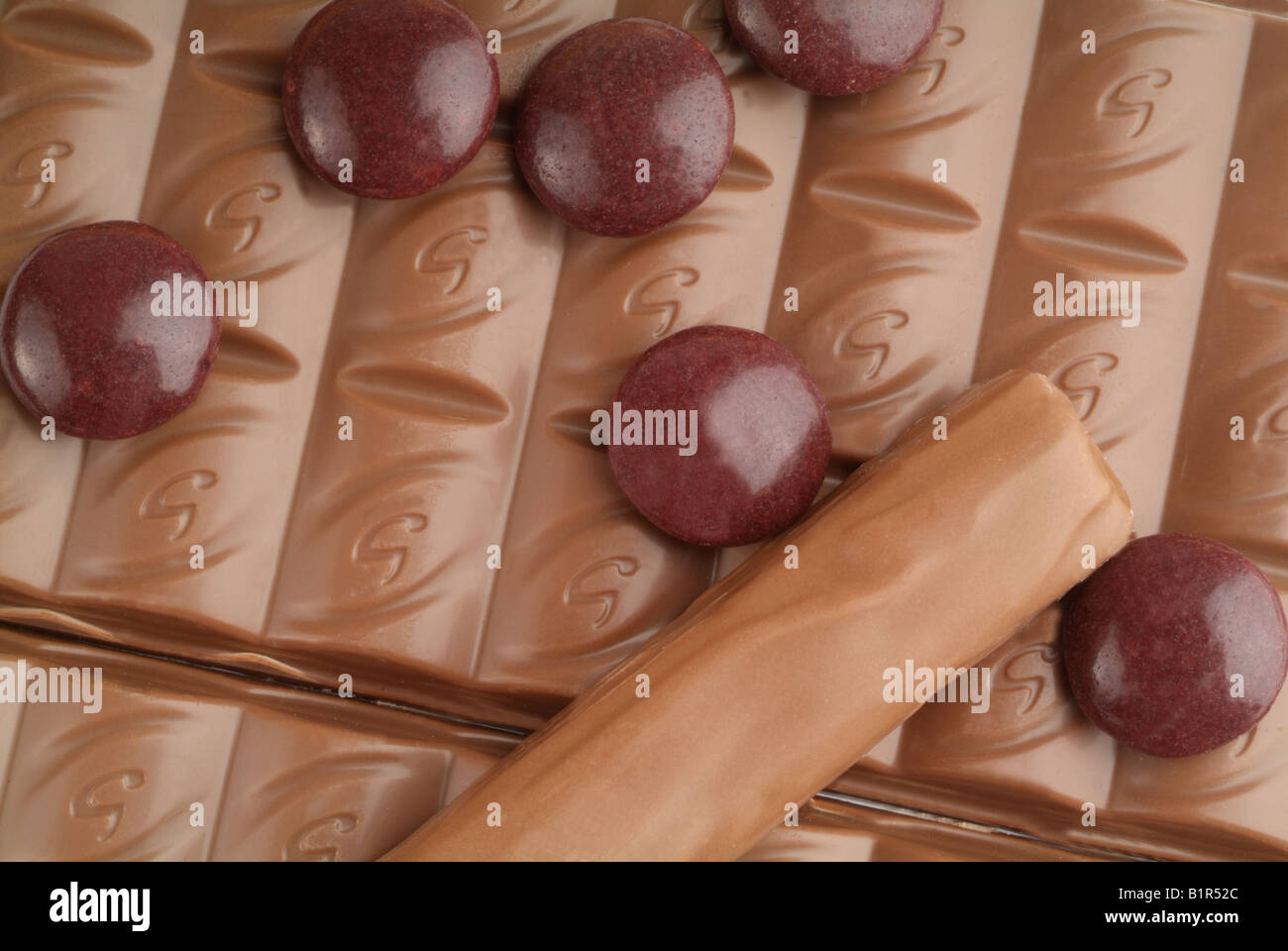 chocolate button type sweets scattered on rows of chocolate bars Stock ...