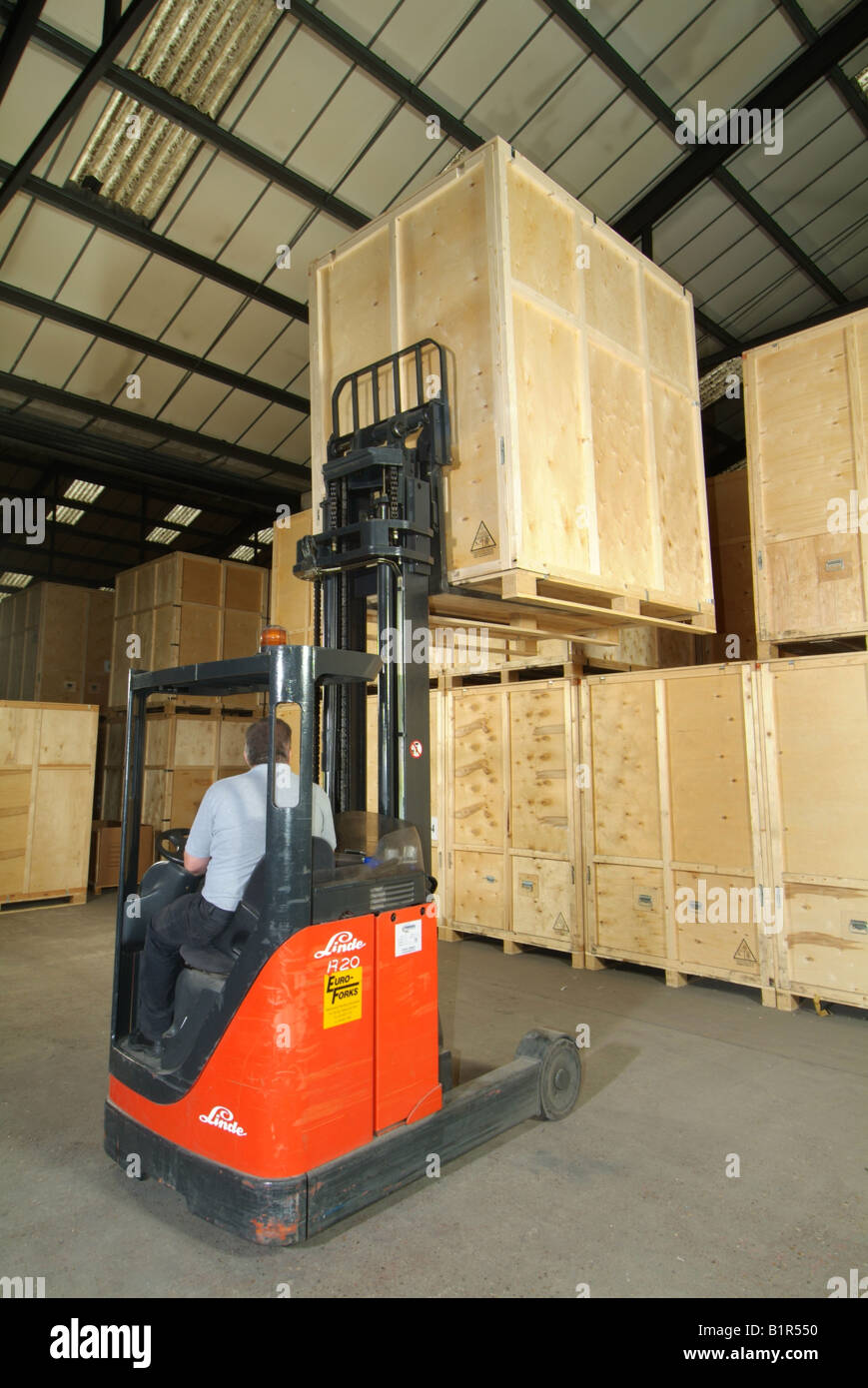 A man operating a fork-lift truck in a warehouse Stock Photo - Alamy