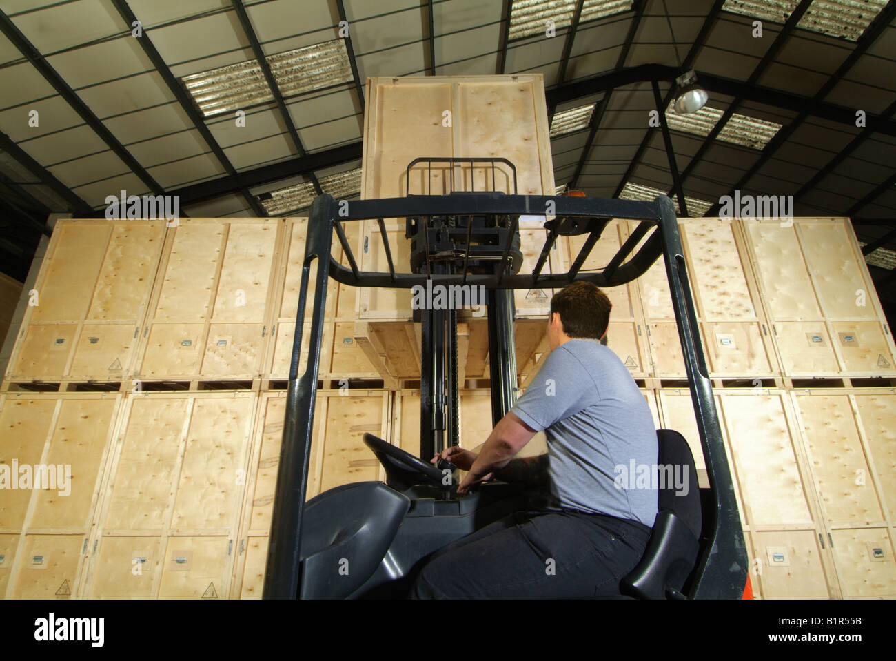 A man operating a fork-lift truck in a warehouse Stock Photo - Alamy