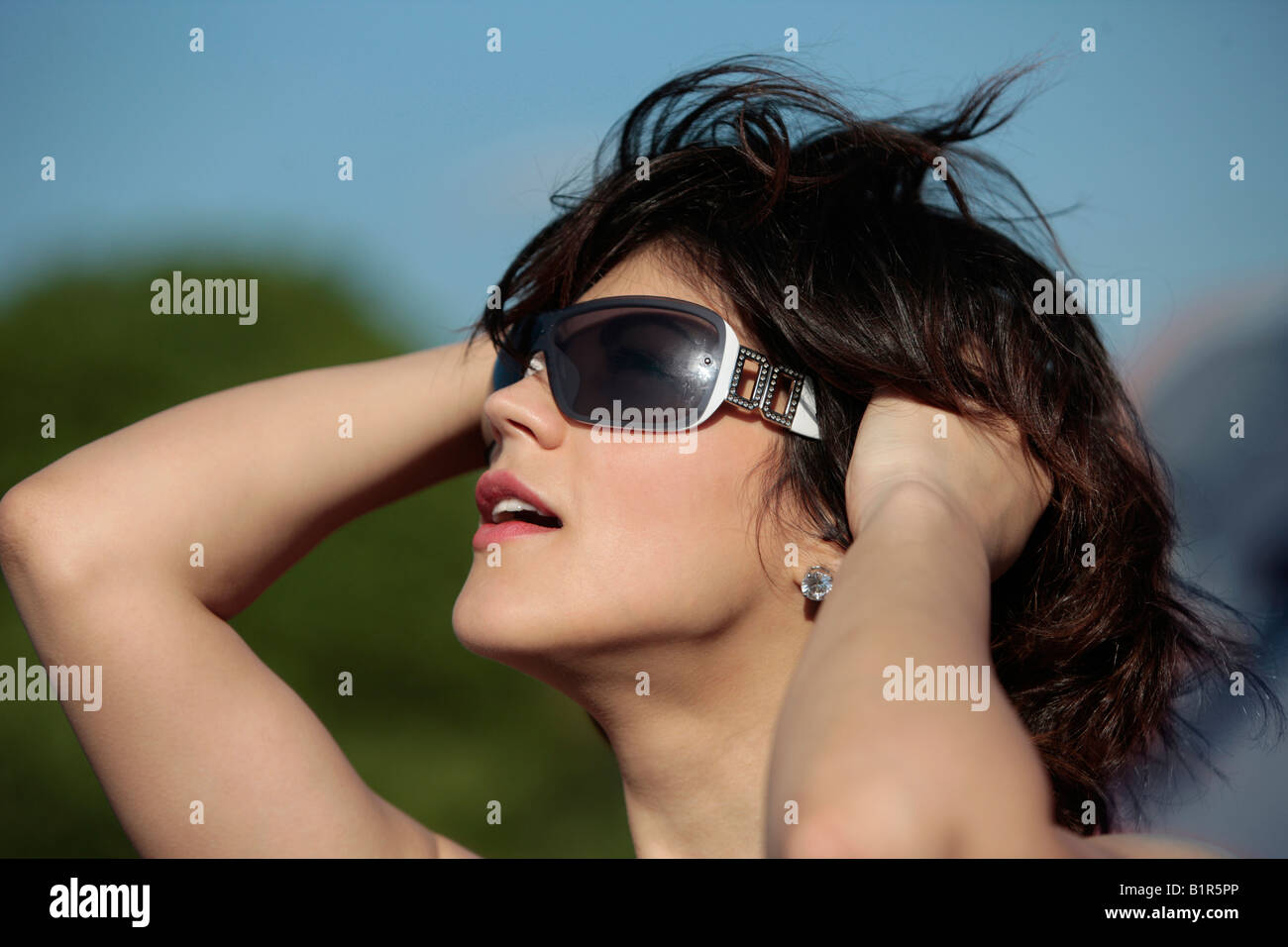 young lady with dark sun glasses outdoor looking at the sun profile ...