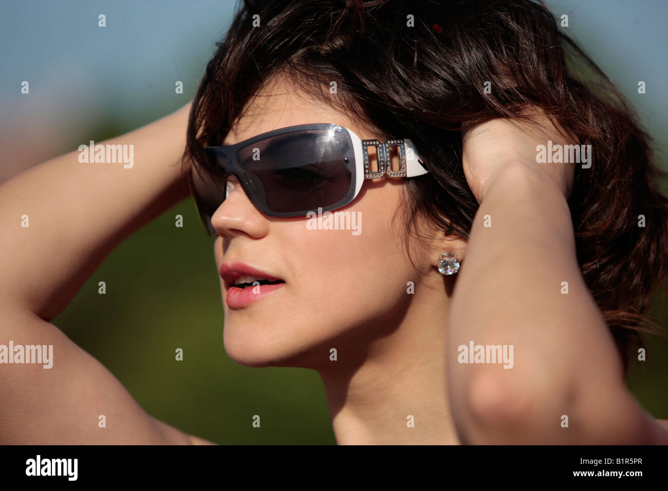 young lady with dark sun glasses outdoor looking at the sun profile ...