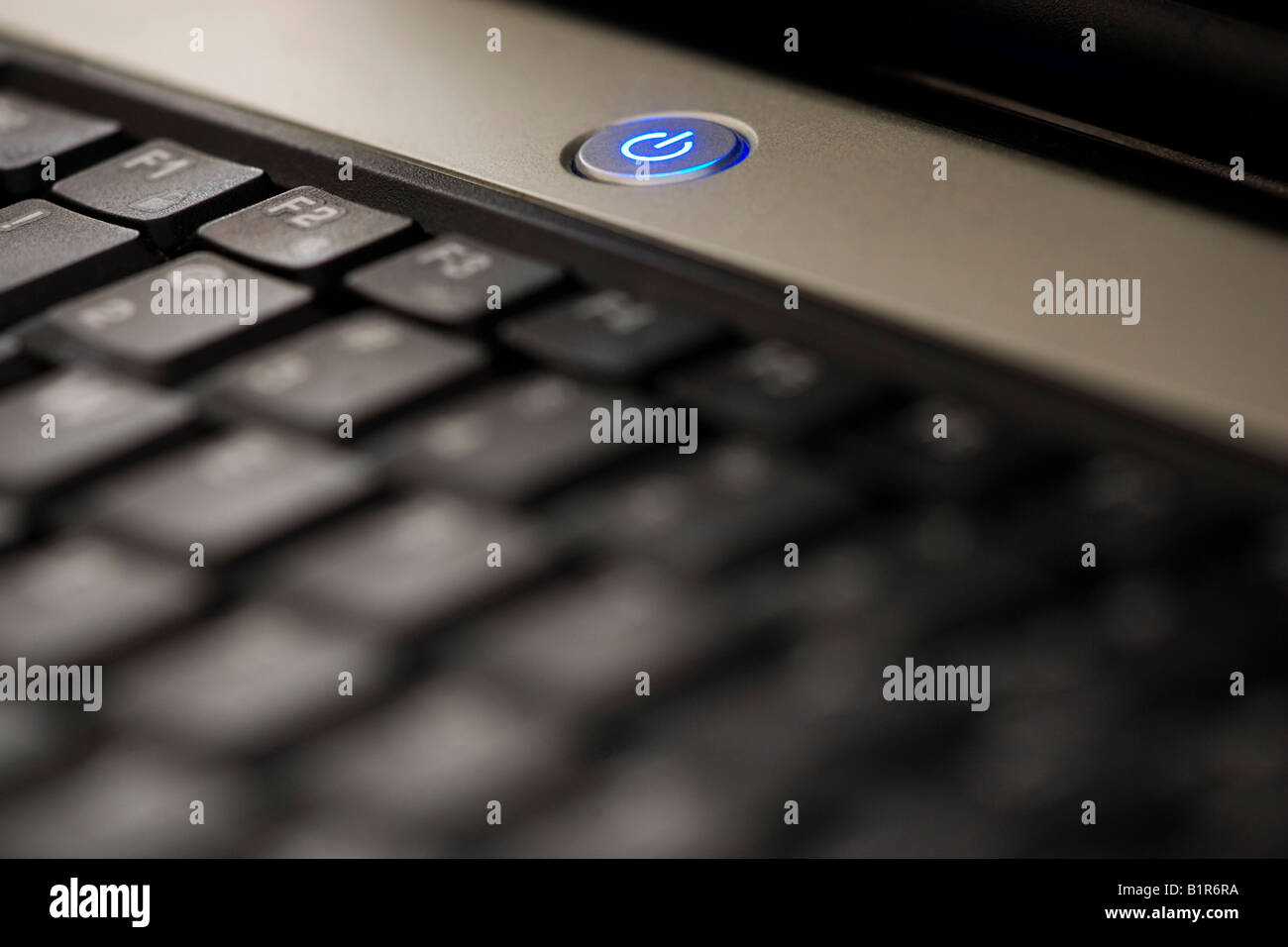 A glowing blue power button on a laptop computer Stock Photo - Alamy