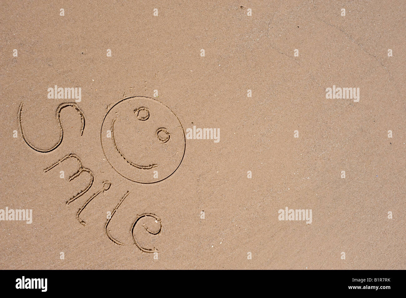 Smile and face drawn in the sand on a beach Stock Photo - Alamy