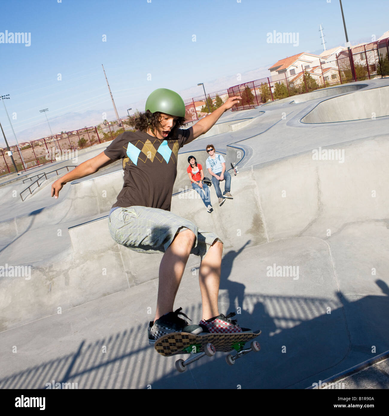 Teen skater does tricks at the skate park with his friends Stock Photo ...