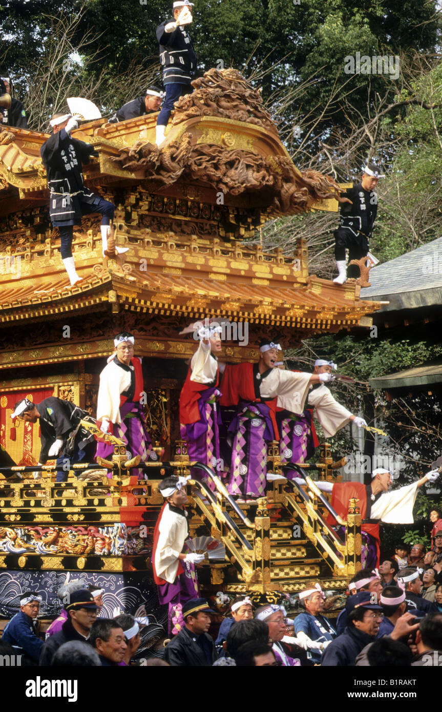 Participants ride on a festival float being pulled through city streets ...
