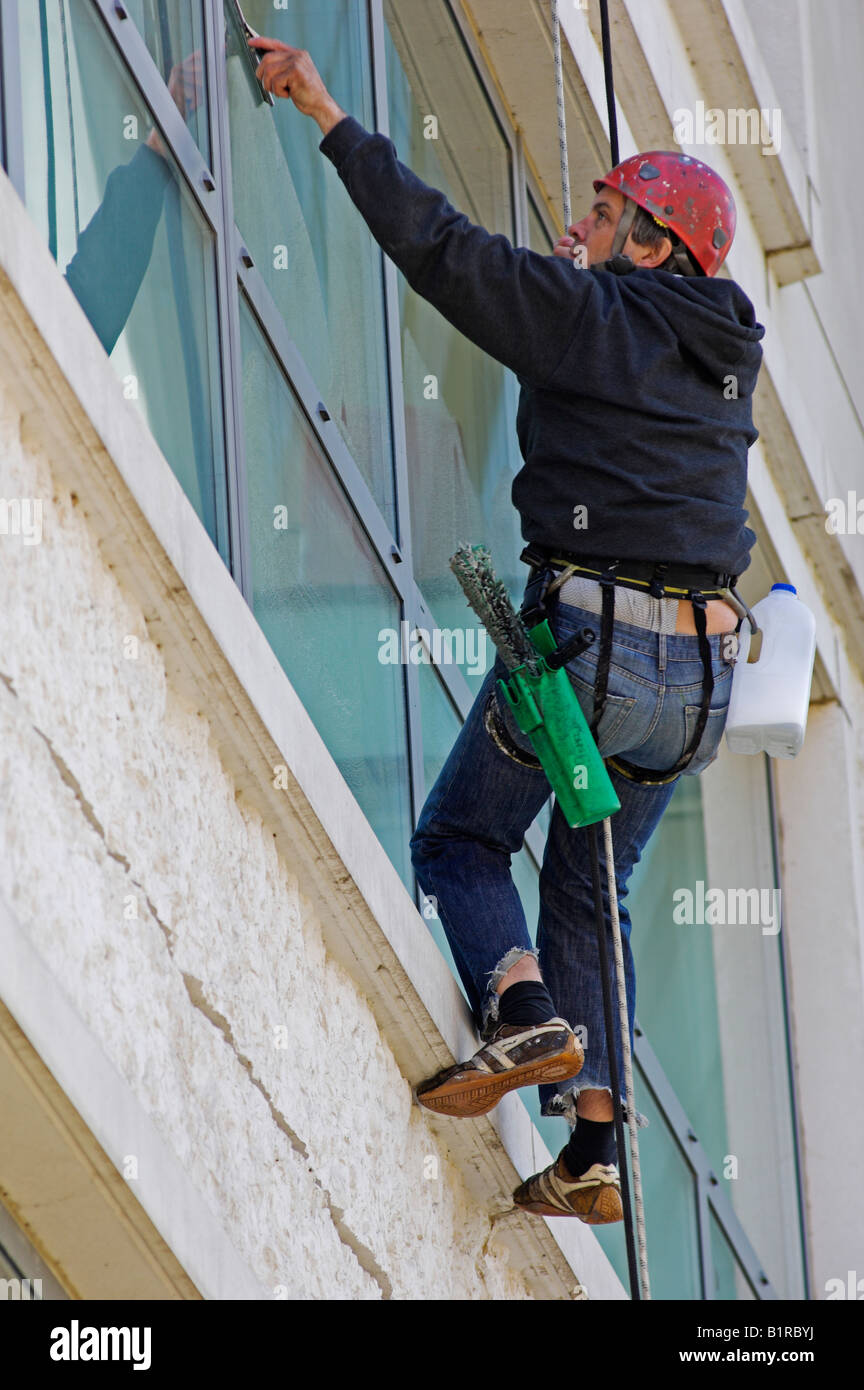 Abseiling [window cleaner] suspended on tall office building cleaning ...
