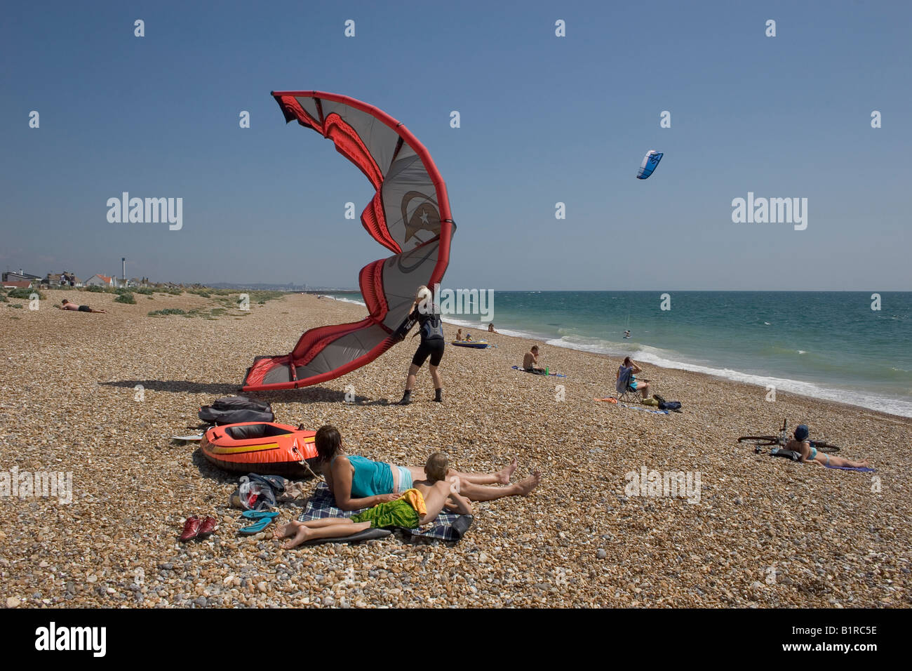 Female Kitesurfer launching kite on beach on the south coast of England ...