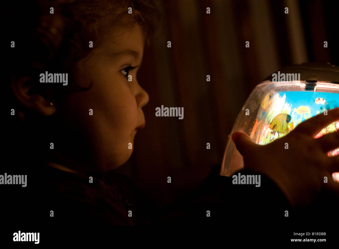 A little one year old girl touching and observing a fancy lamp in a ...