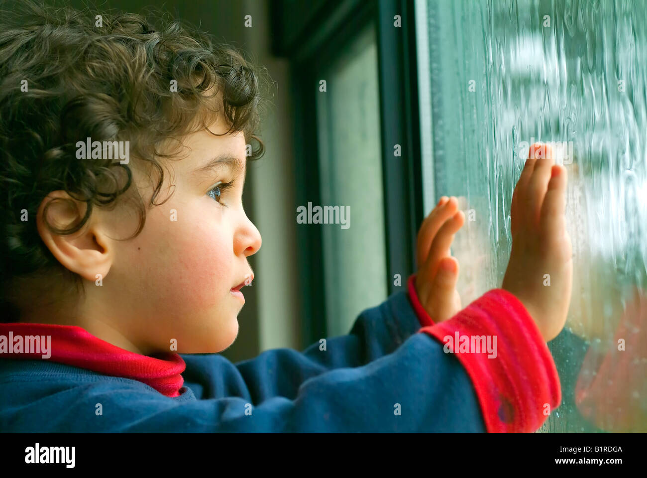 little boy watching the rain through the window Stock Photo - Alamy