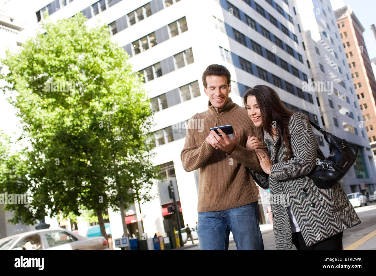 A young couple are strolling arm in arm through a downtown city area ...