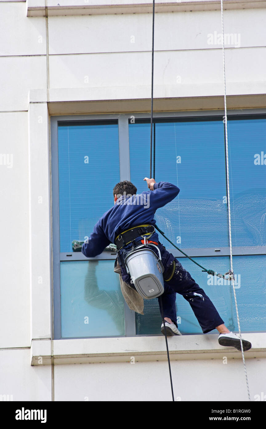 Window cleaner abseiling down on tall office building to work Stock ...