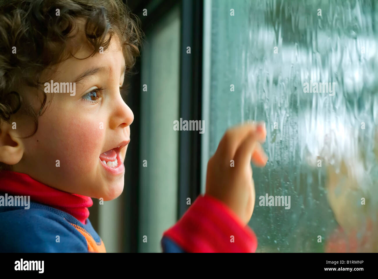 little boy watching the rain through the window Stock Photo - Alamy