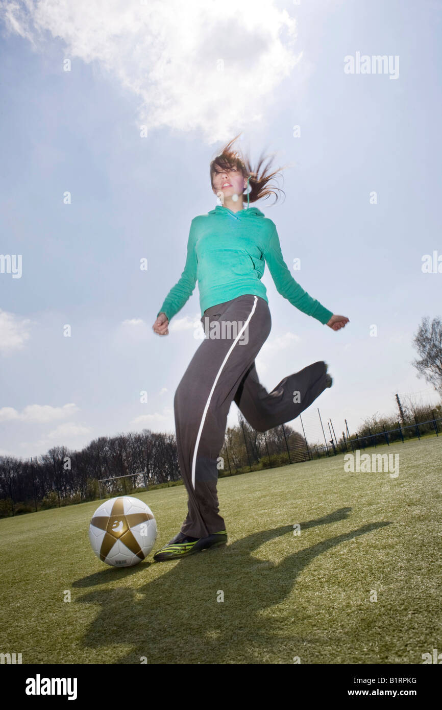 Young woman playing football on a sports field Stock Photo - Alamy