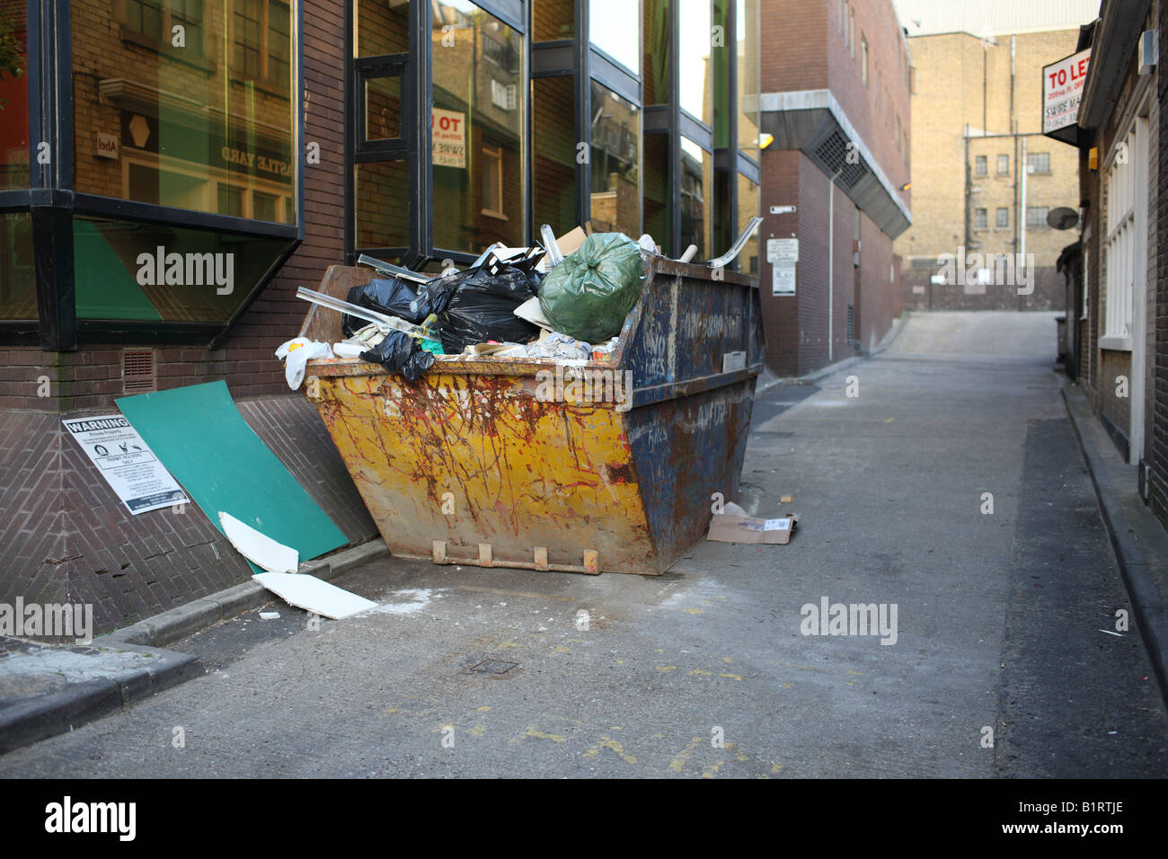 A fully loaded skip, in a sidestreet Stock Photo - Alamy