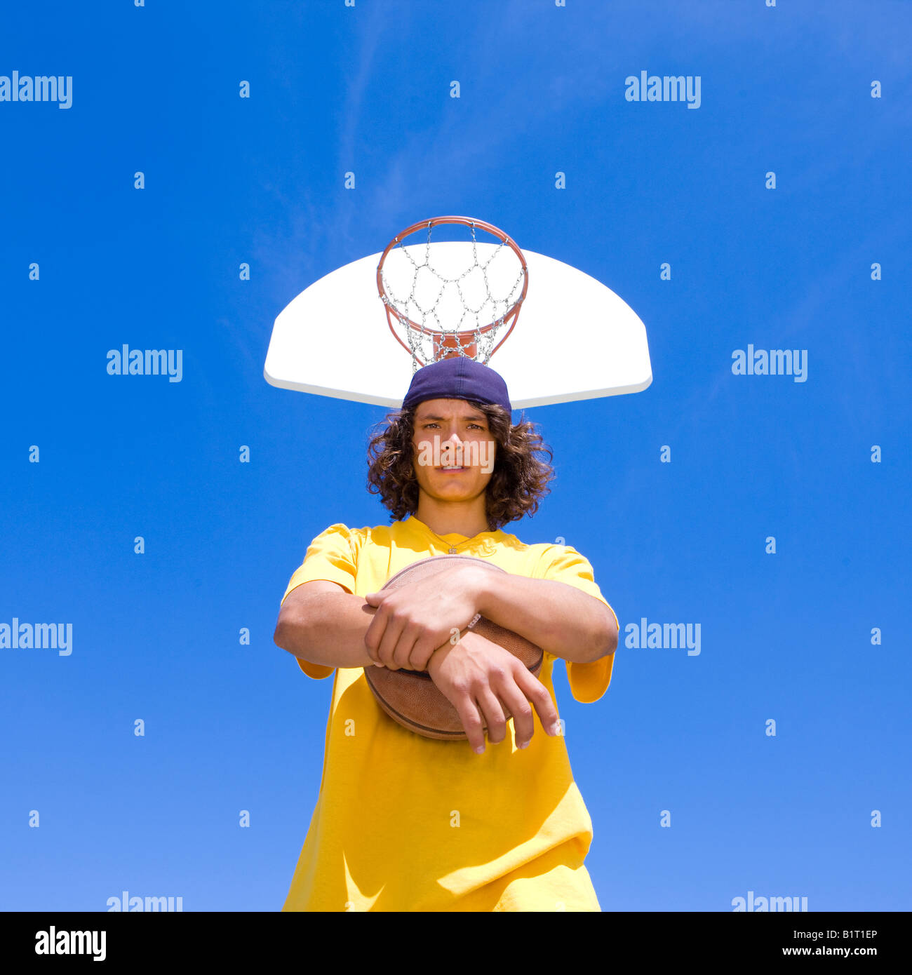A teen basketball player stands below the backboard Stock Photo - Alamy