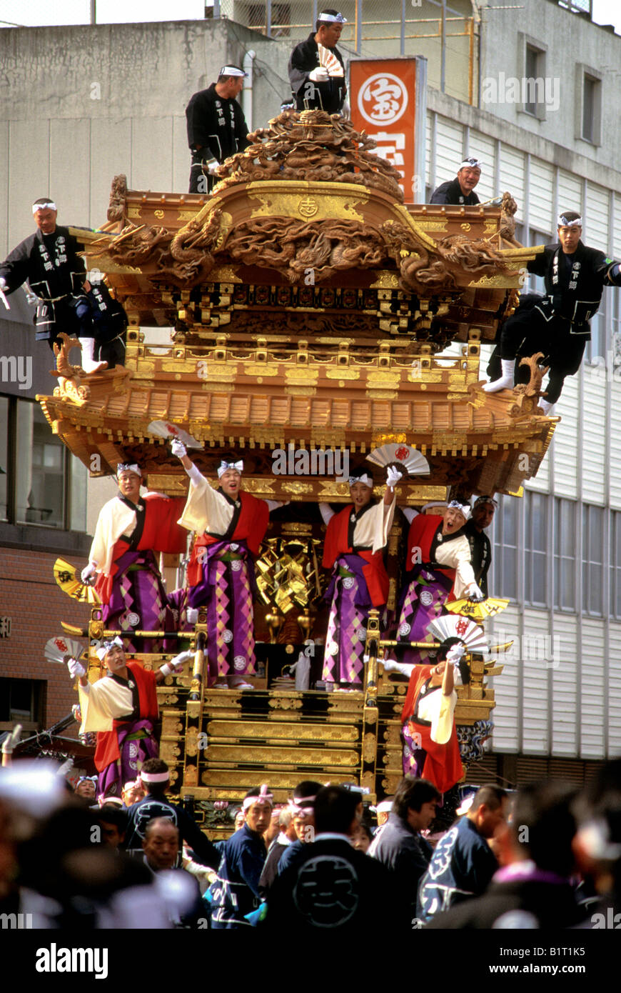 Participants ride on a festival float being pulled through city streets ...