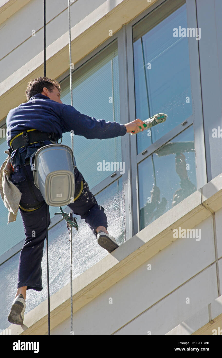 Absailing [window cleaner] suspended on tall office building cleaning ...