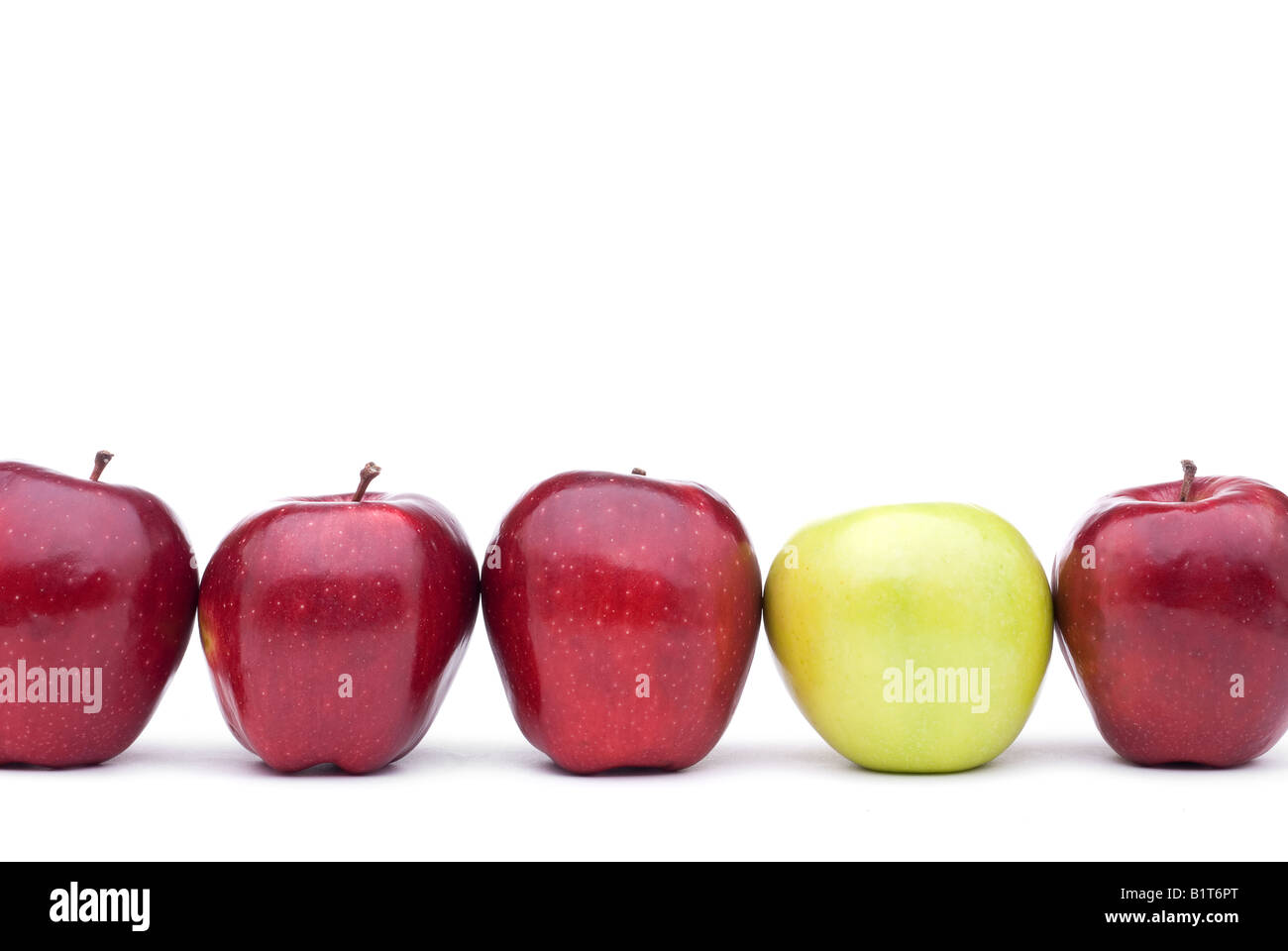 Red apples lined up on a white background with a single different green ...
