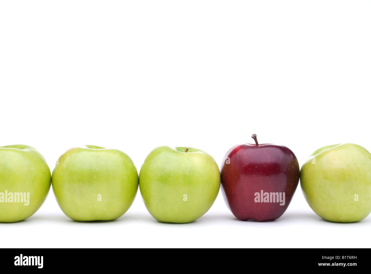 Green apples lined up on a white background with a single different red ...
