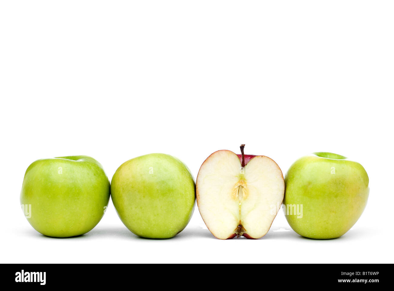 Green apples lined up on a white background with a single different ...