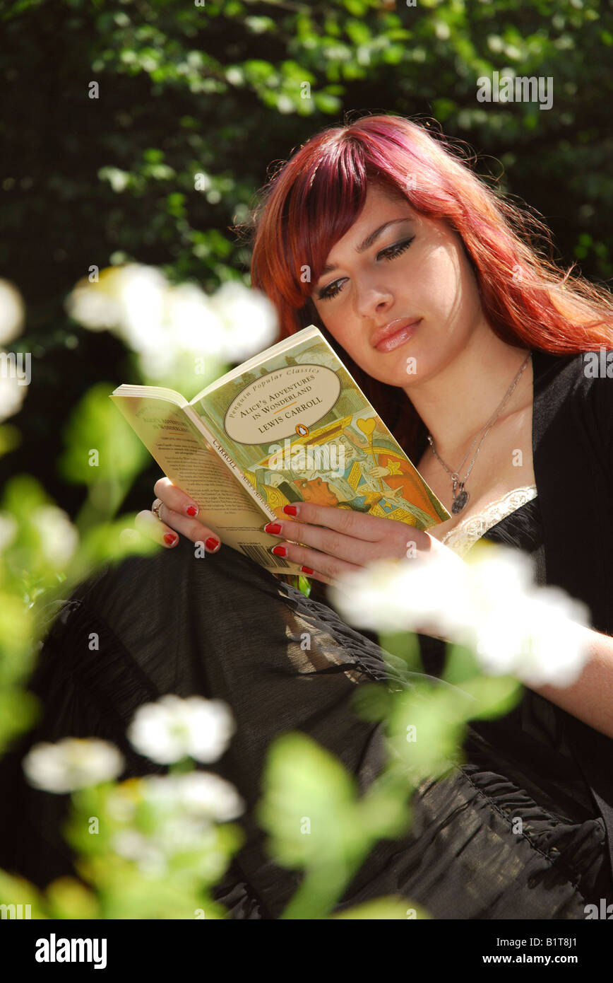 girl reading Alice in Wonderland seated on a park bench Stock Photo - Alamy