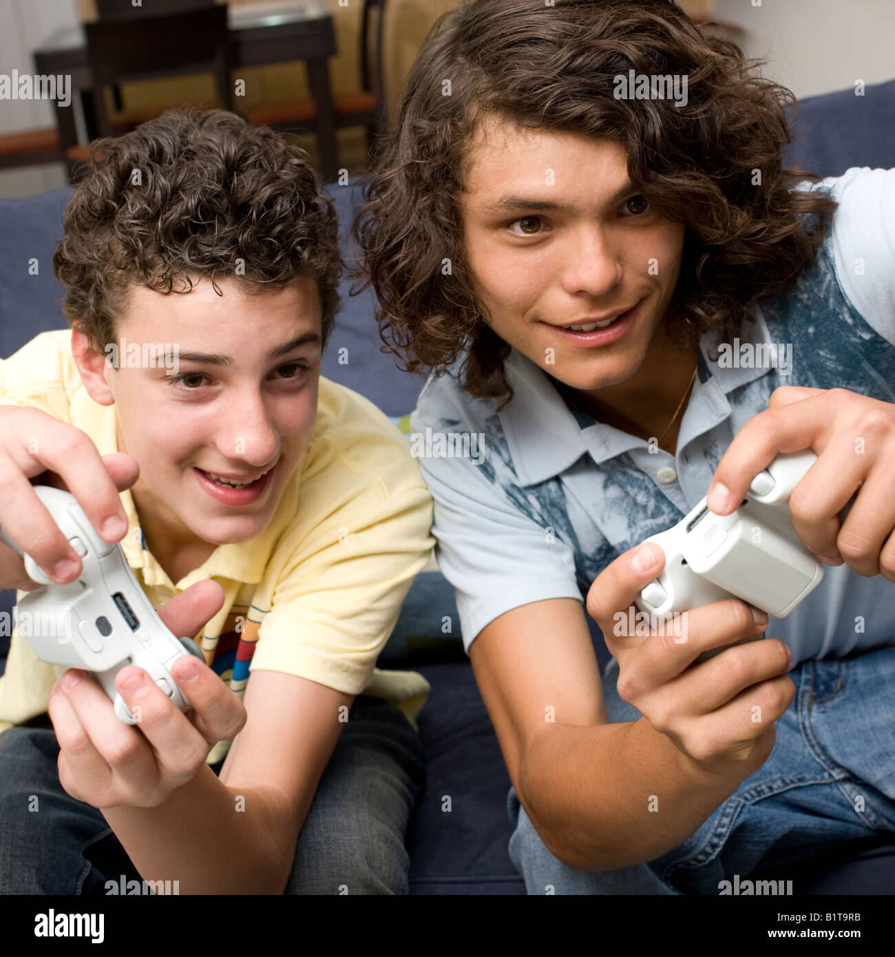 Two guys play videogames on a couch Stock Photo - Alamy