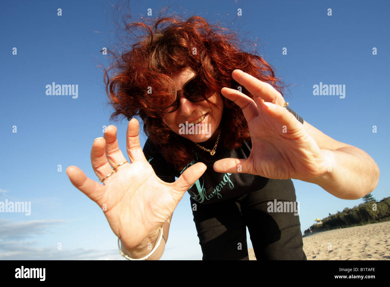 A VIVACIOUS RED HAIRED WOMAN LOOKING INTO THE CAMERA WITH HANDS ...