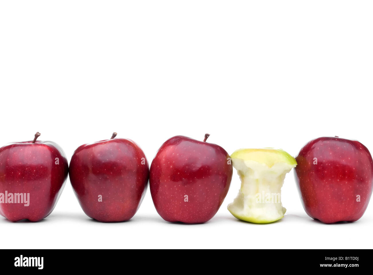 Red apples lined up on a white background with a single eaten green ...