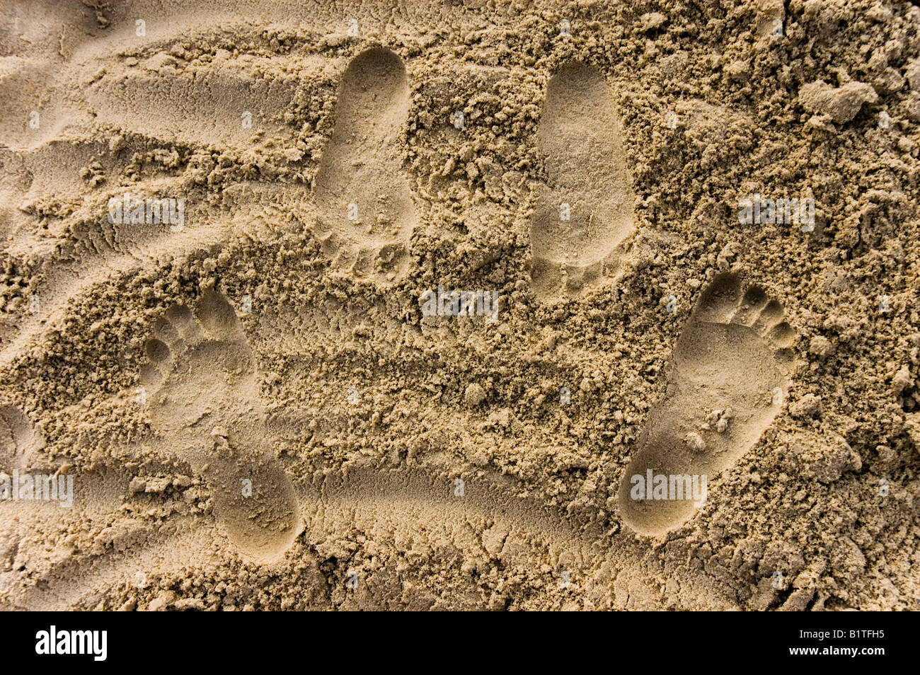 Footprints in the sand of a couple hugging The feet are facing one ...