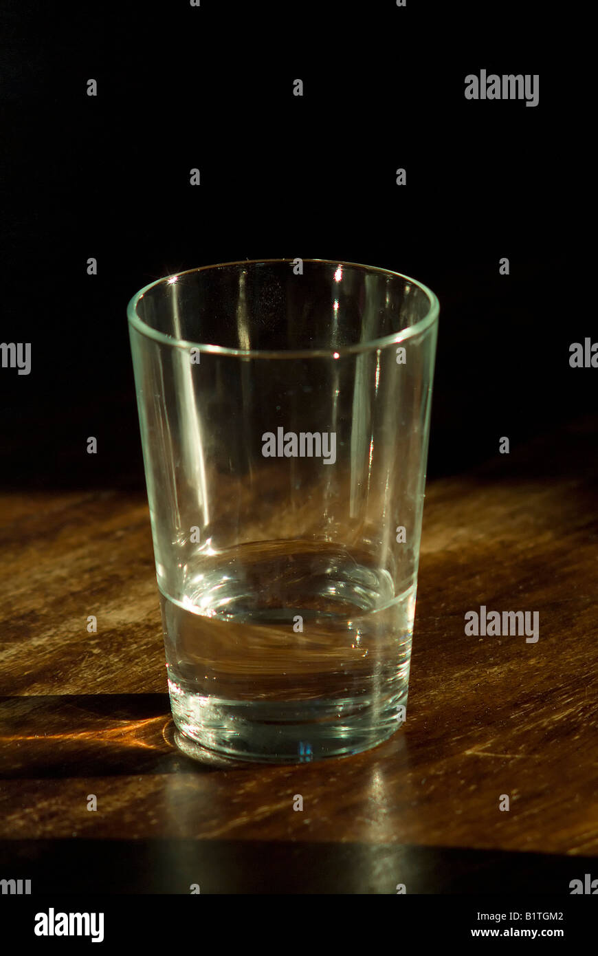 almost empty glass of water on a wooden surface Stock Photo - Alamy
