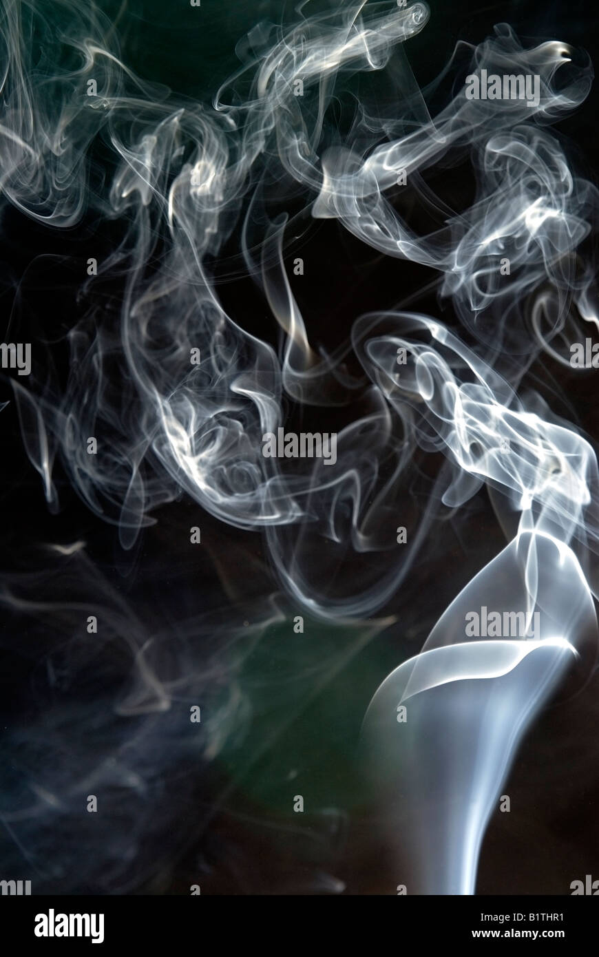 White smoke pattern from a burning incense stick against a black ...