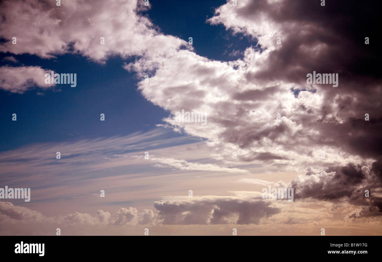 Big dark brooding black storm cloud moving in on a rich blue sunset sky ...