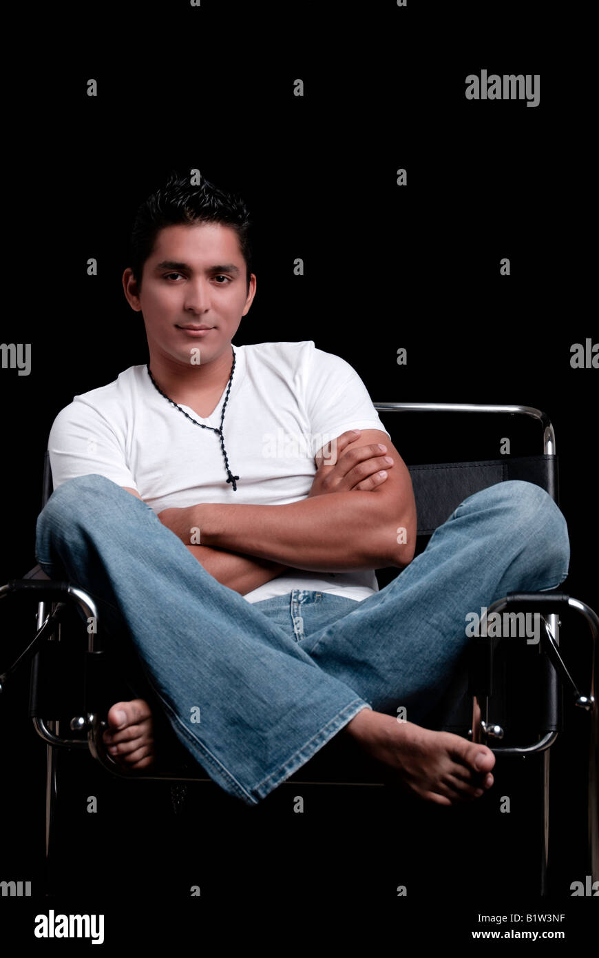 Studio shot of a young man seatting comfortably on a chair, over a ...