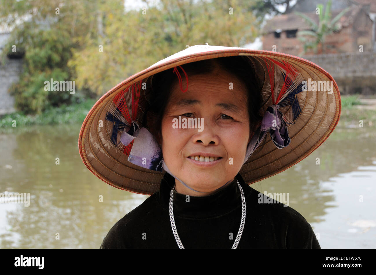 Vietnamese woman wearing a traditional conical hat tied with ribbons ...