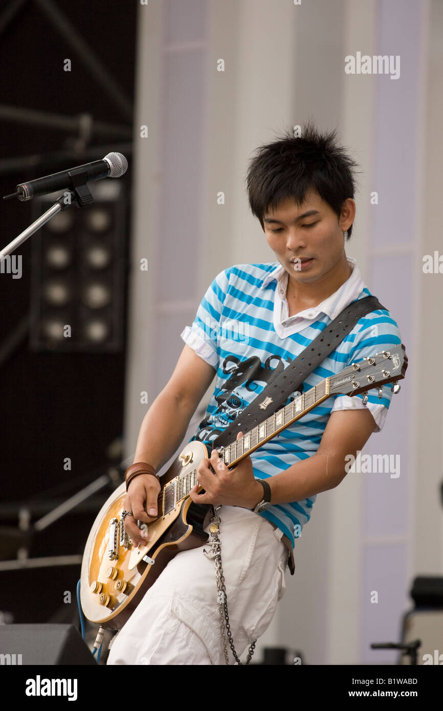 Young Asian male guitarist performing onstage at an outdoor concert in ...