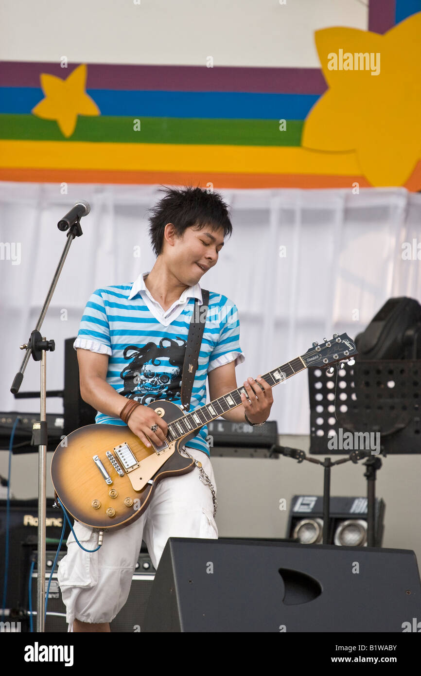 Young Asian male guitarist performing onstage at an outdoor concert in ...