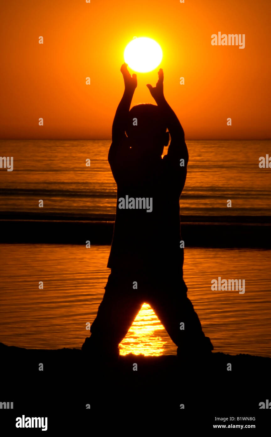 Boy holding the sun on a beach during the sunset Stock Photo - Alamy