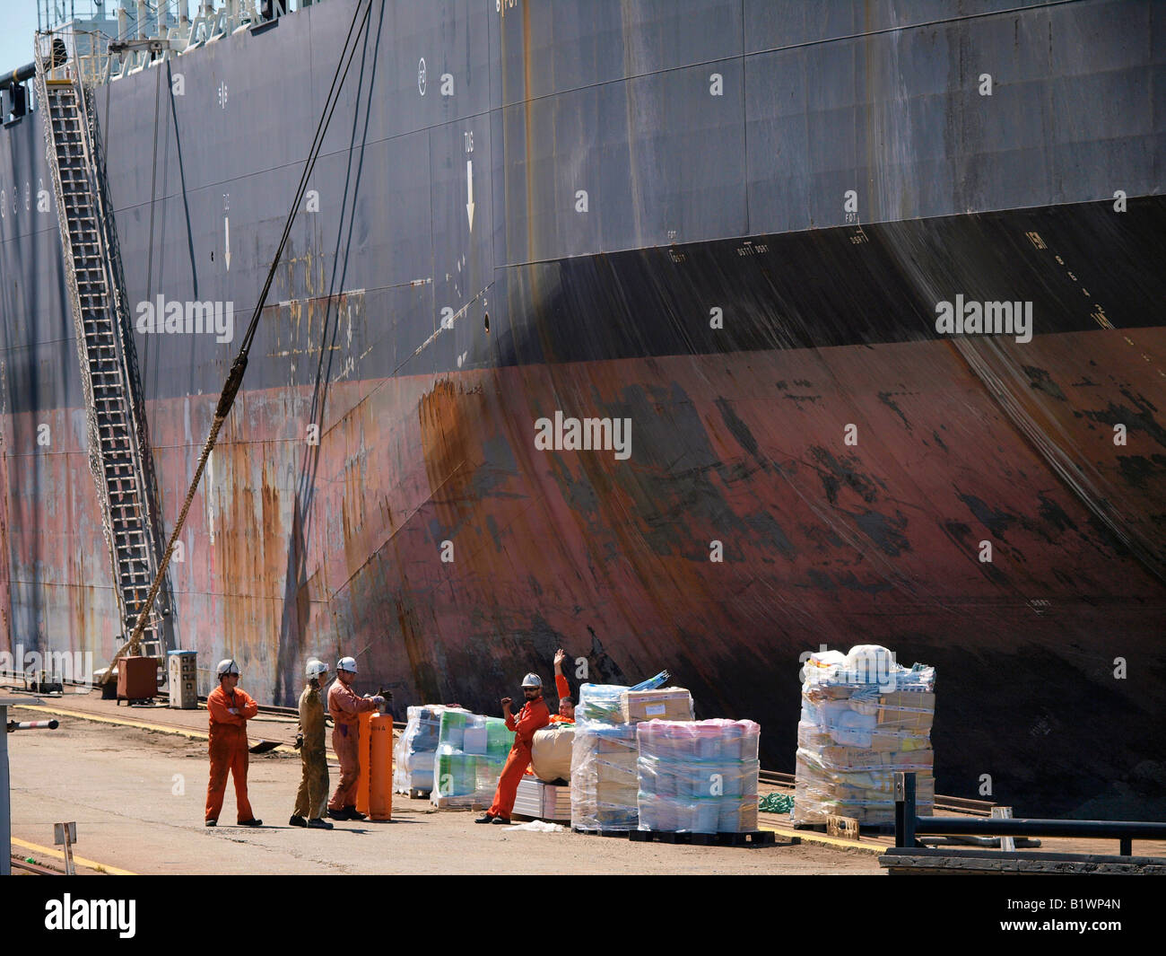 People at work near a very large ship in the port of Antwerp Belgium ...
