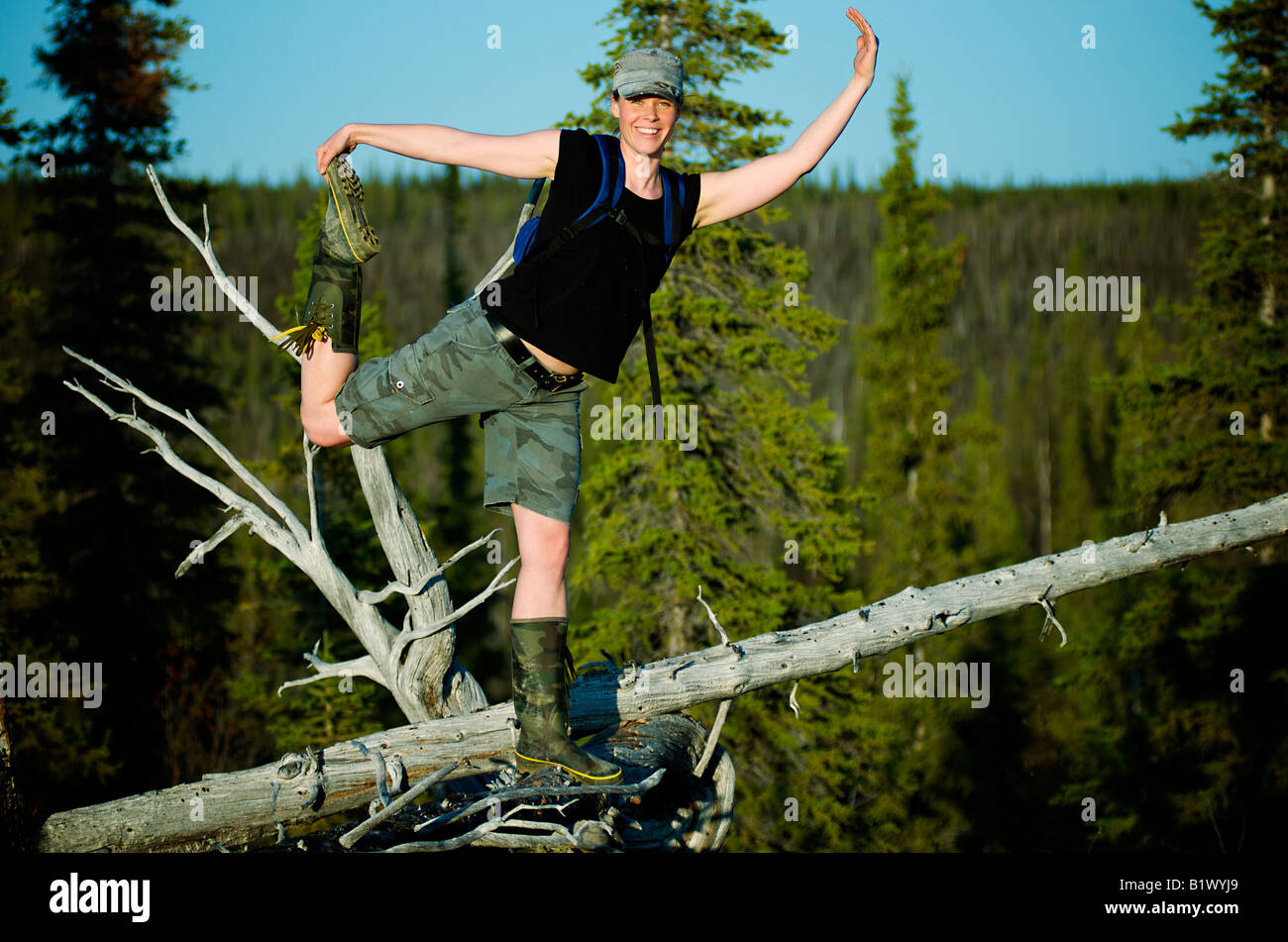 Fit, trendy, smiling young woman doing a yoga stance on a log. Big ...