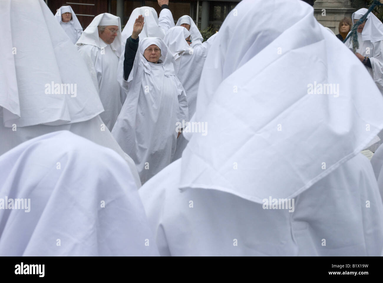 A member of The Druid Order, in white robes, raises a hand raised in ...