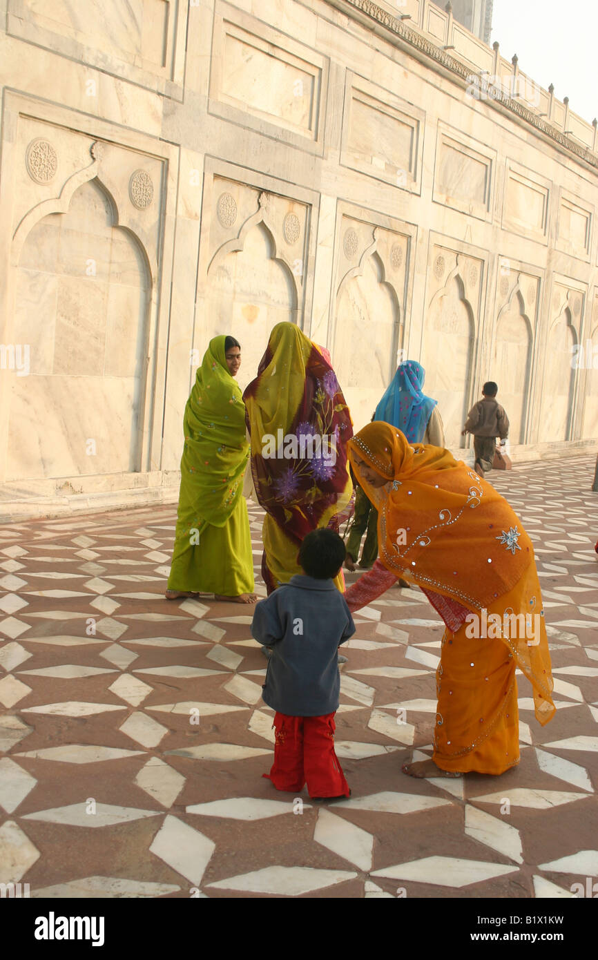 indian women in brightly coloured saris walking up to Taj Mahal at dawn ...