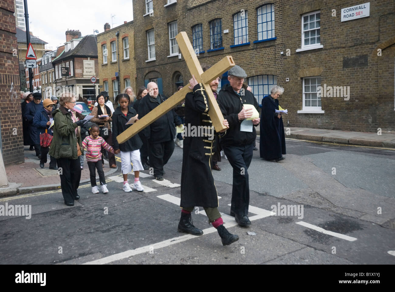 Man crosses road carrying wooden cross in Good Friday Walk of Witness ...