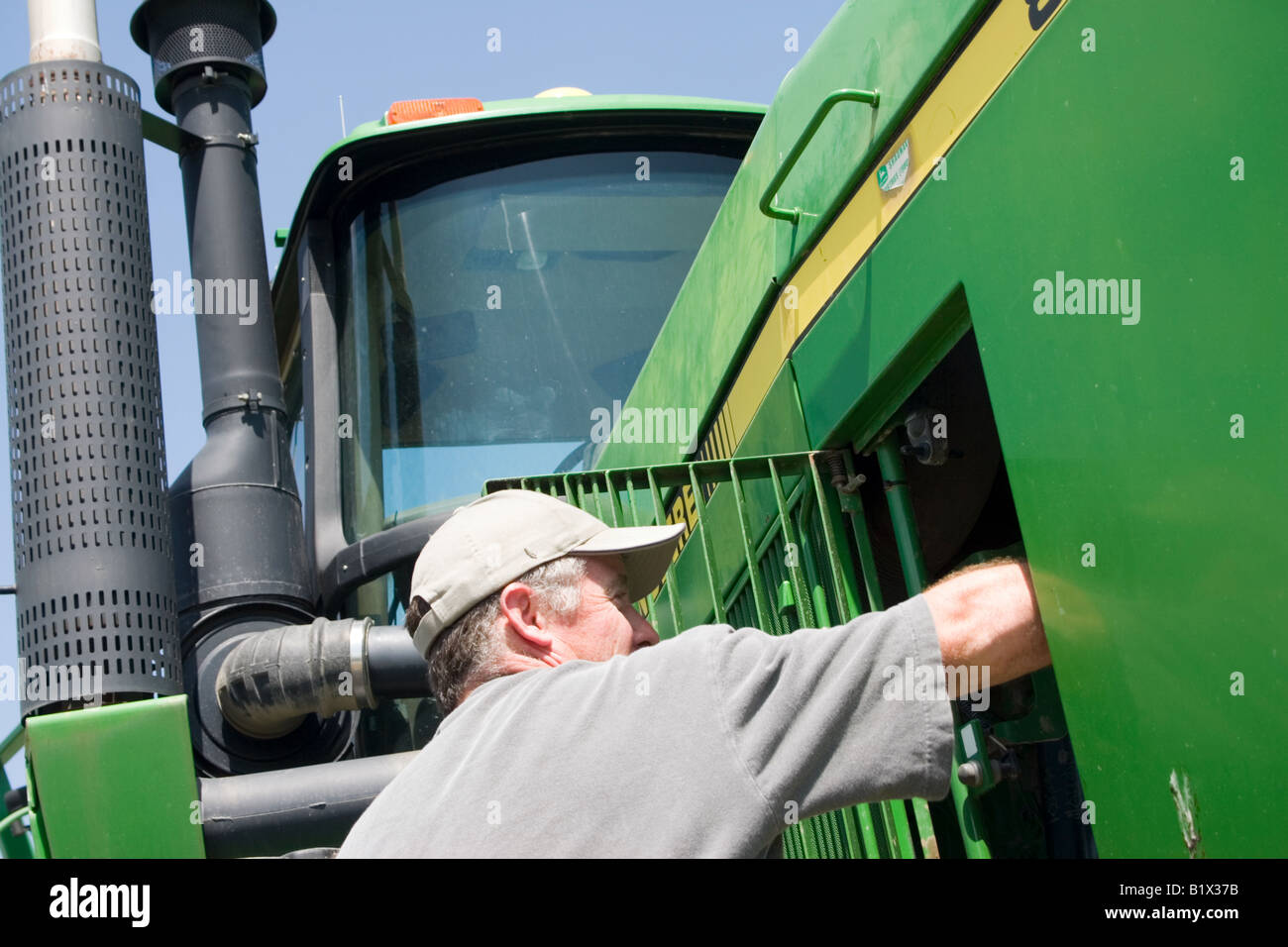A farmer does a check on his tractor before starting up on a farm in ...