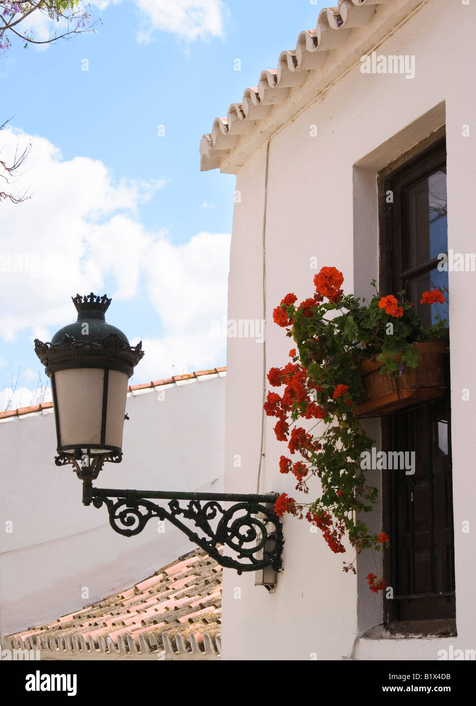 Typical Spanish window with red geraniums and lamp Stock Photo - Alamy